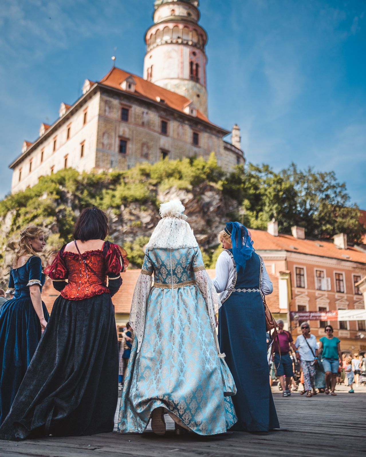 A group of women in medieval attire walking on a cobblestone street ...